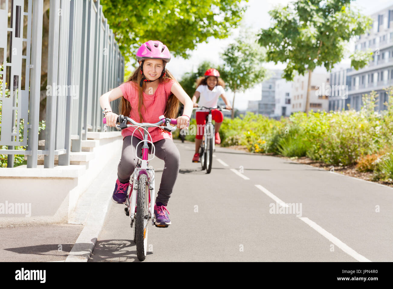Girl riding bicycle catching up with her friend Stock Photo - Alamy
