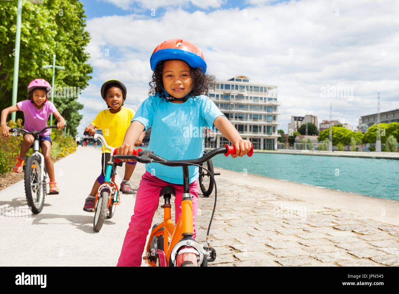 Cute African girl riding bike ahead of her friends Stock Photo - Alamy
