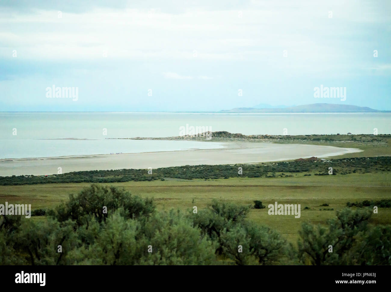 A curved beach at the Great Salt Lake with a mountain behind it on a ...