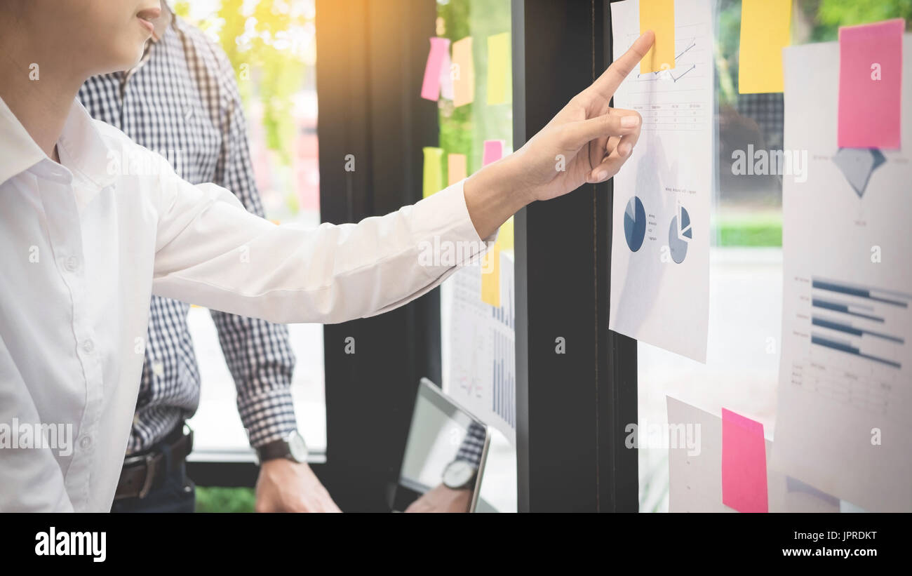 business man sticking adhesive notes on glass wall in office and ...