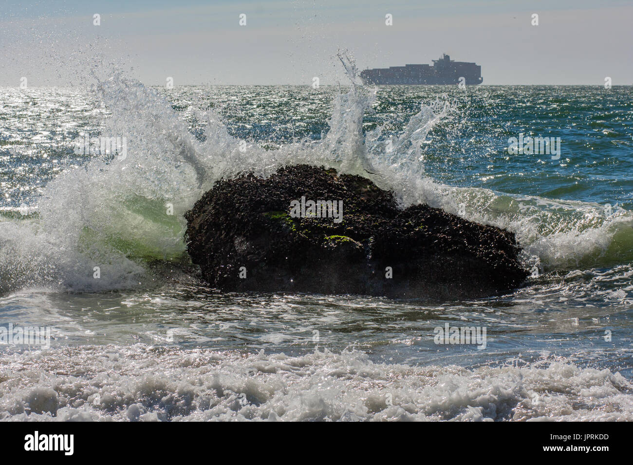 water crashing into rock with boat in background Stock Photo - Alamy