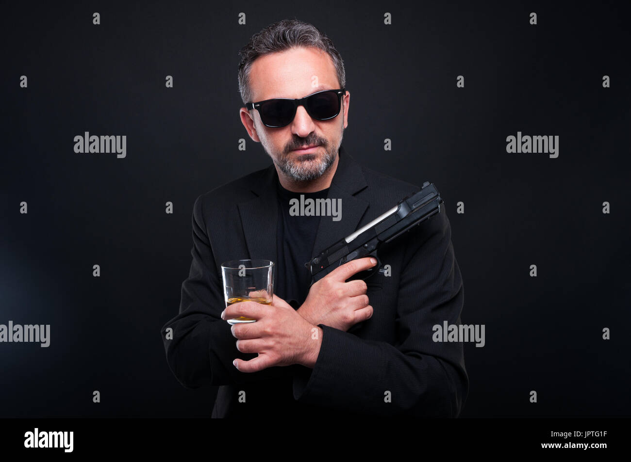 Dangerous mafia boss drinking scotch and holding his gun Stock Photo ...