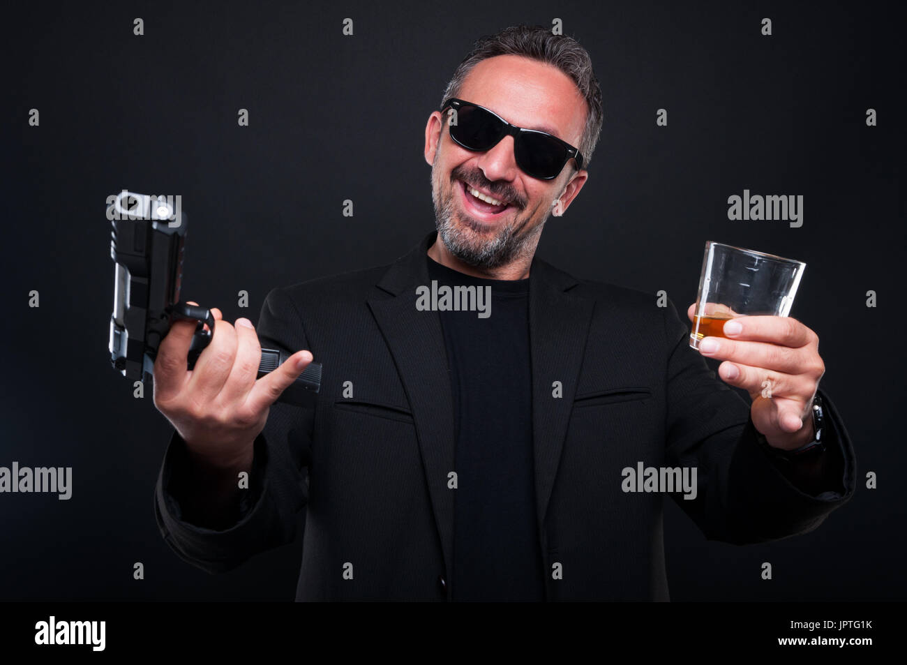 Cheerful mafia member partying and drinking whiskey on black background ...