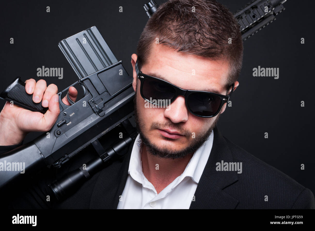 Closeup portrait of male gangster with automatic weapon looking at the ...
