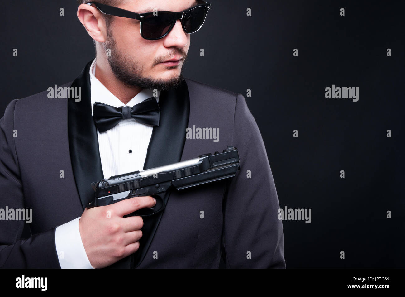 Handsome mafia member or secret agent with armed revolver on black ...
