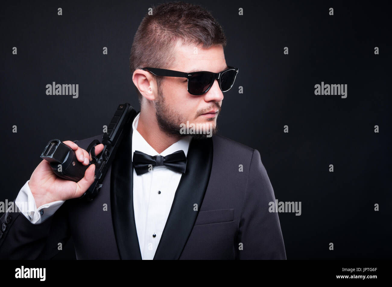 Portrait of handsome shooter posing with his weapon in dark background ...