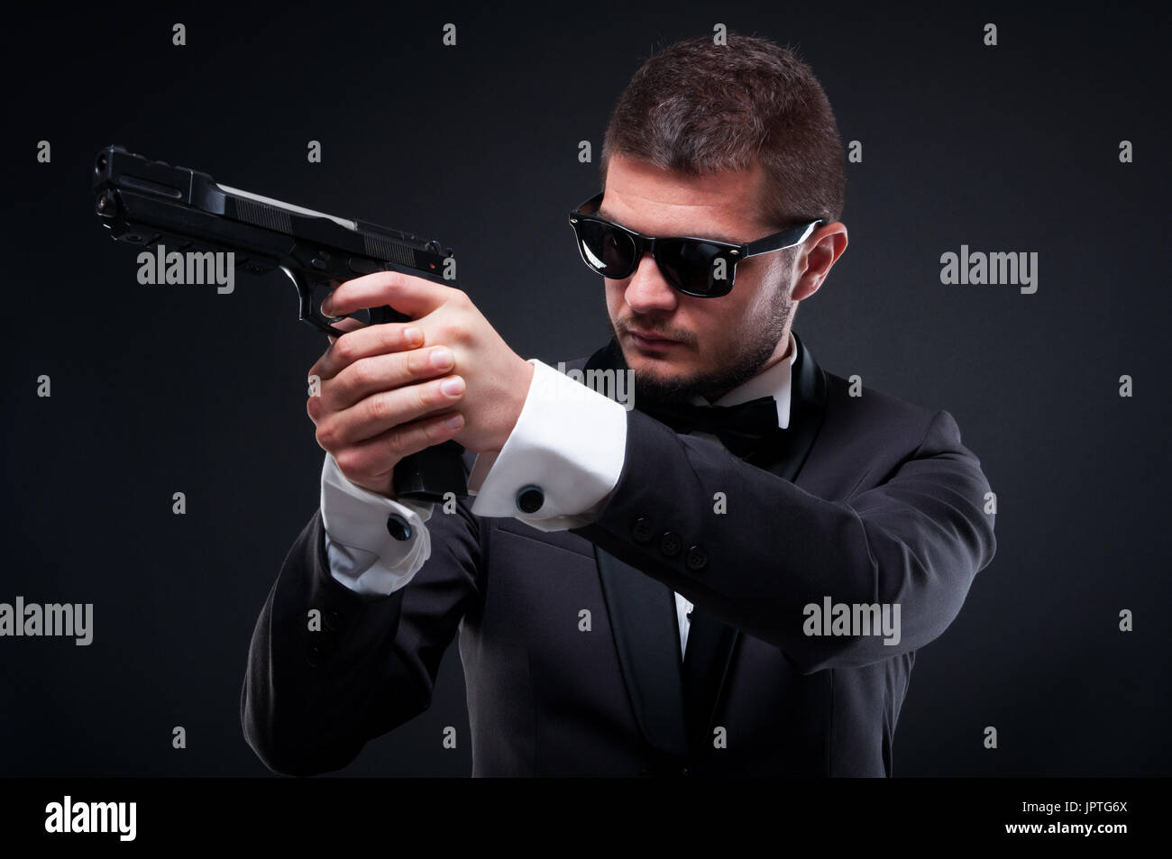 Aggressive gunman aiming pistol at his target on dark background Stock ...