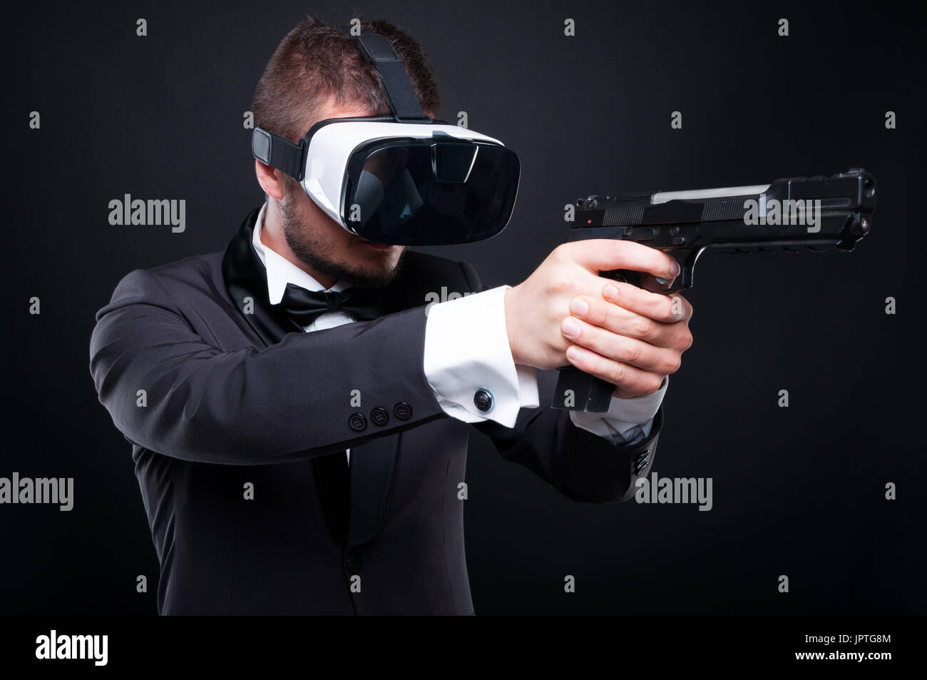 Dangerous man with a gun and vr goggles shooting on black background ...