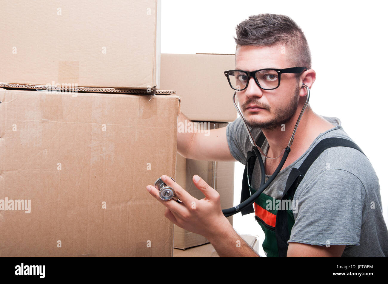 Mover guy posing holding cardboard box with stethoscope looking curious ...