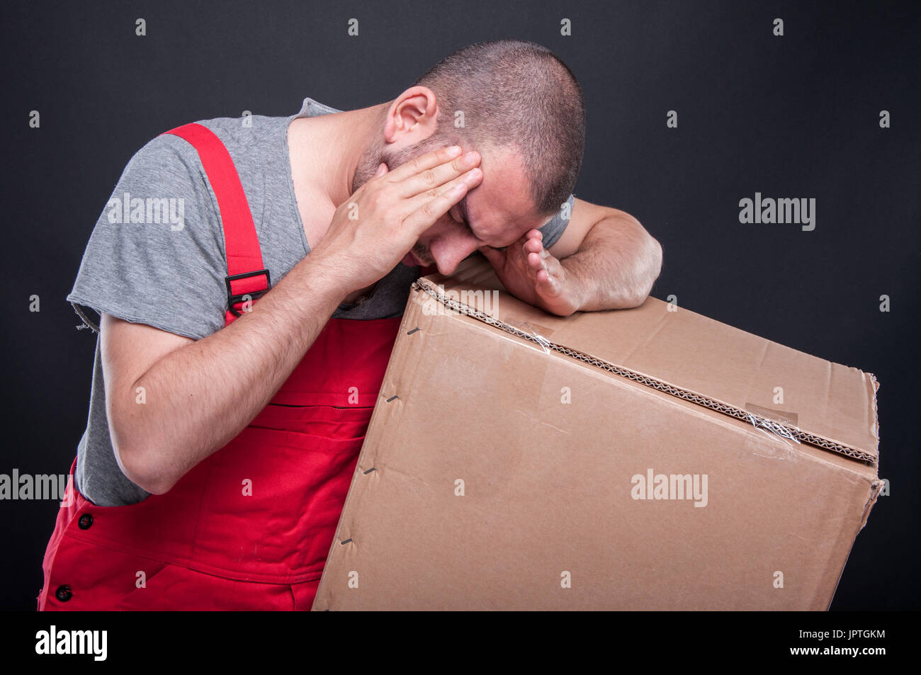 Mover man holding box having head ache gesture on black background ...