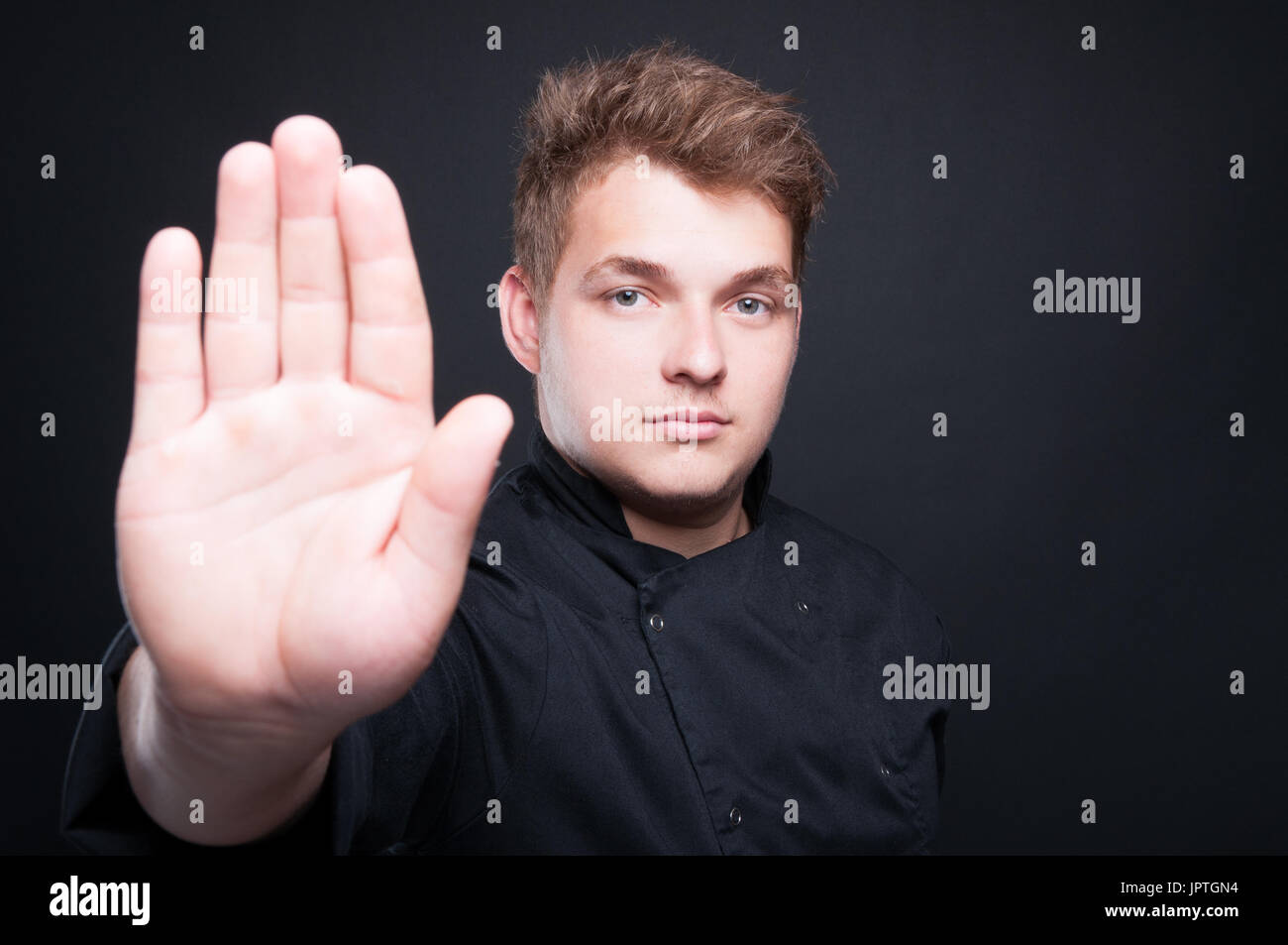 Handsome cooking chef showing stop sign with his palm isolated on dark ...