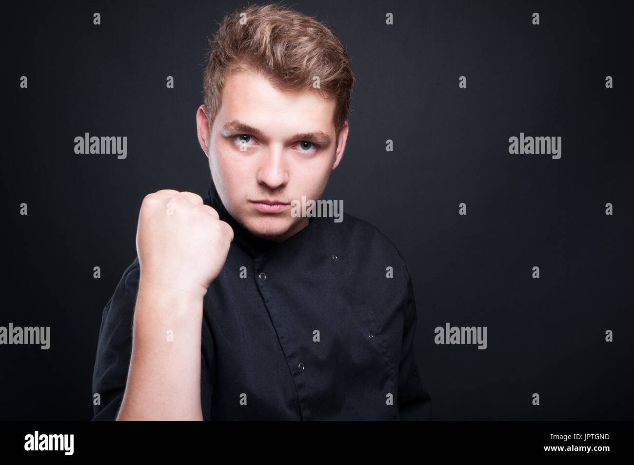 Aggressive cook holding up his fist arguing with somebody on dark ...