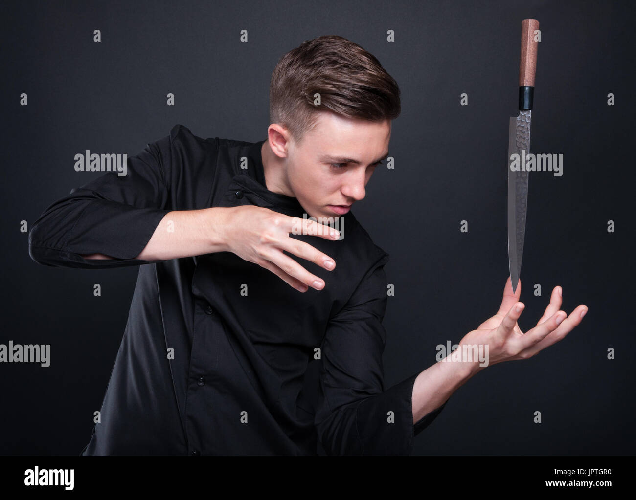 Talented cook or chef making magic with his knife on dark studio ...