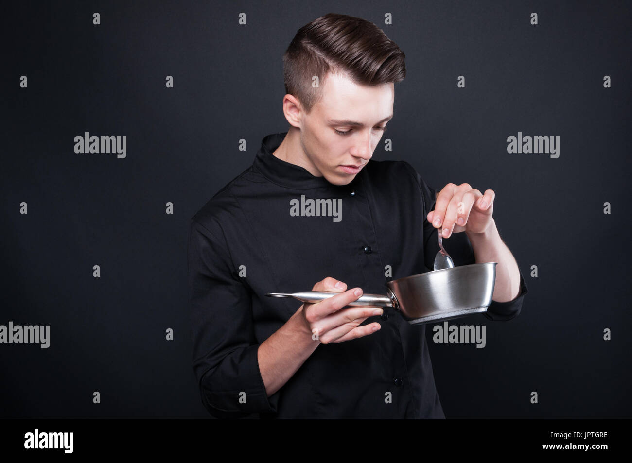 Successful and talented chef making a great sauce in small pan on dark ...