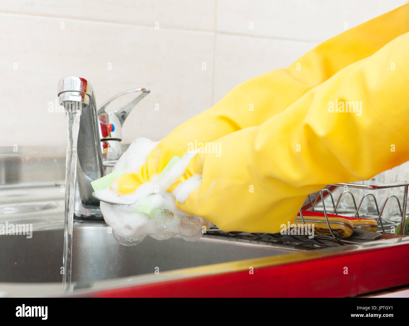 Female hands washing cutlery in the sink with pouring water in closeup ...