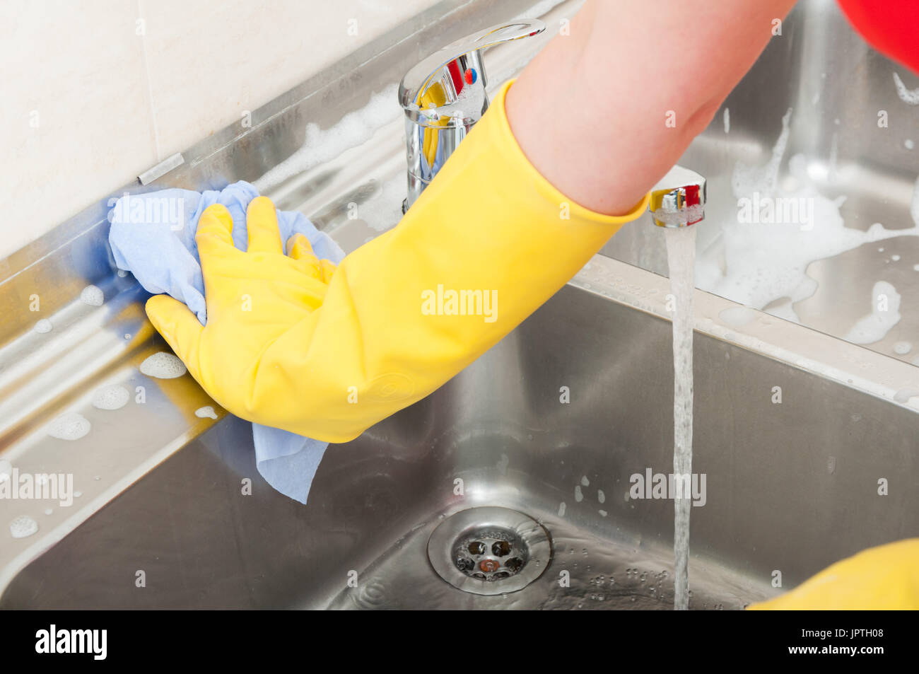Water flowing from the faucet in the sink and woman hand wiping with ...