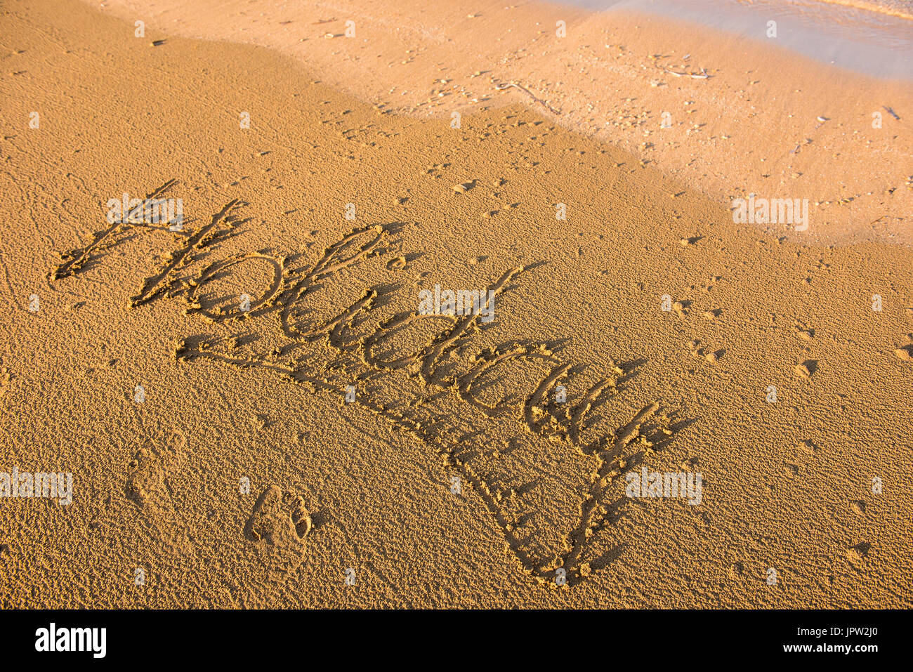 Holiday word written in sand. Summer beach concept Stock Photo - Alamy
