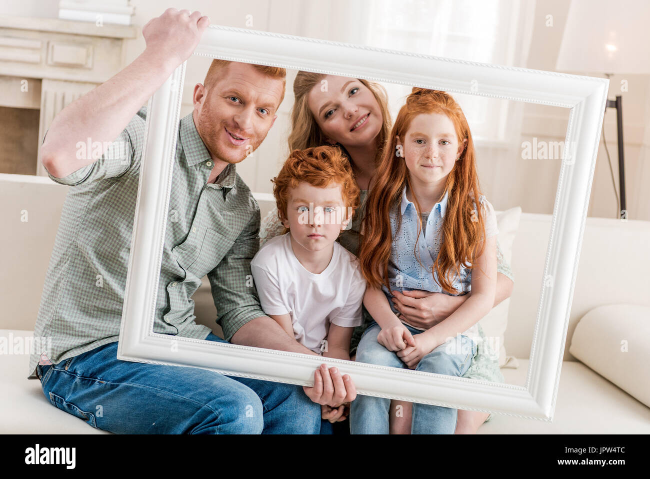 happy redhead family looking through white frame together, big family ...