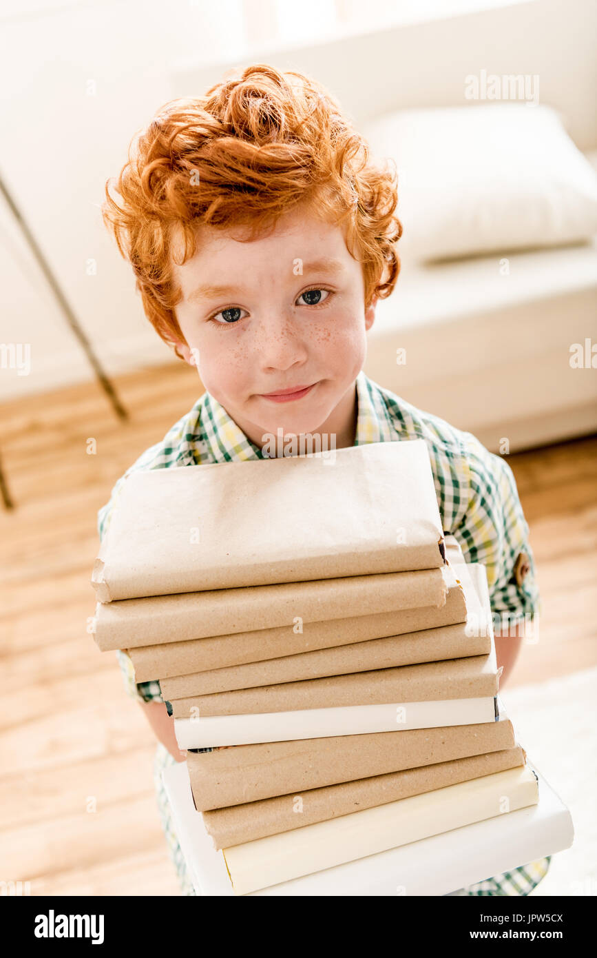 Portrait of thoughtful little boy holding pile of books Stock Photo - Alamy