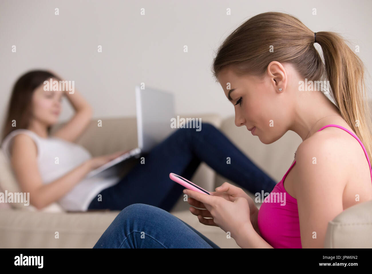 Girlfriends using electronic gadgets at home Stock Photo - Alamy