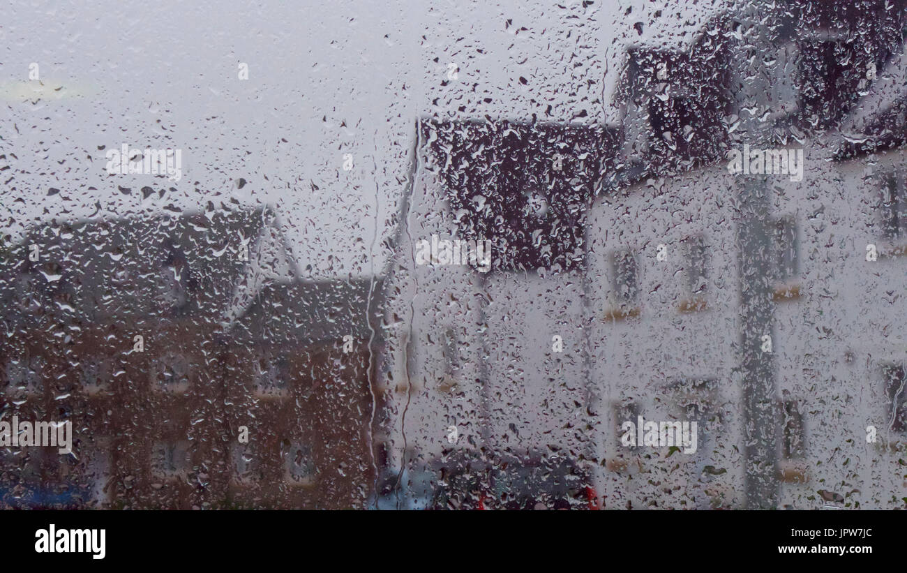 Looking through a raindrop covered window at houses on a rainy summers ...