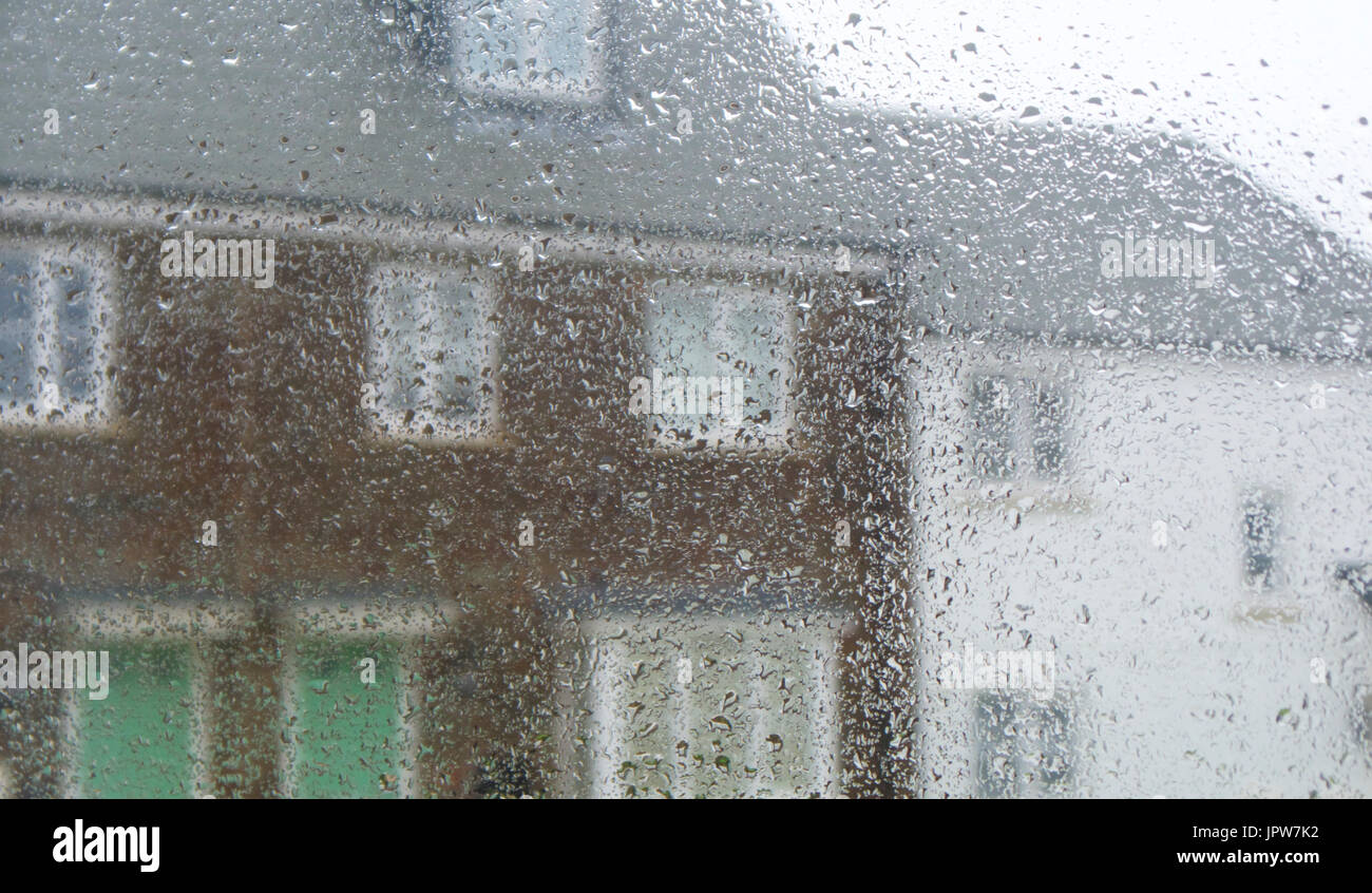 Looking through a raindrop covered window at houses on a rainy summers ...