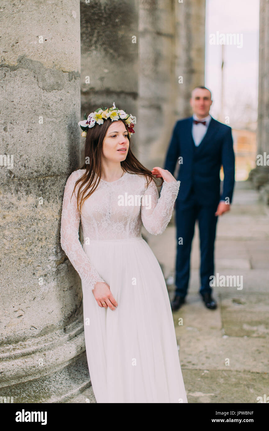 Young wedding couple standing outside near atique building with columns ...