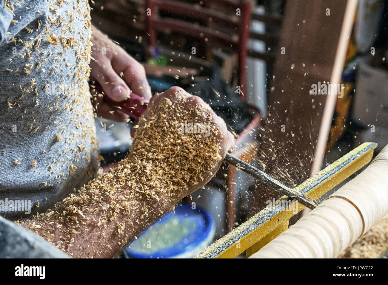 A young, strong man makes a wooden product on a lathe, lathe work, many ...