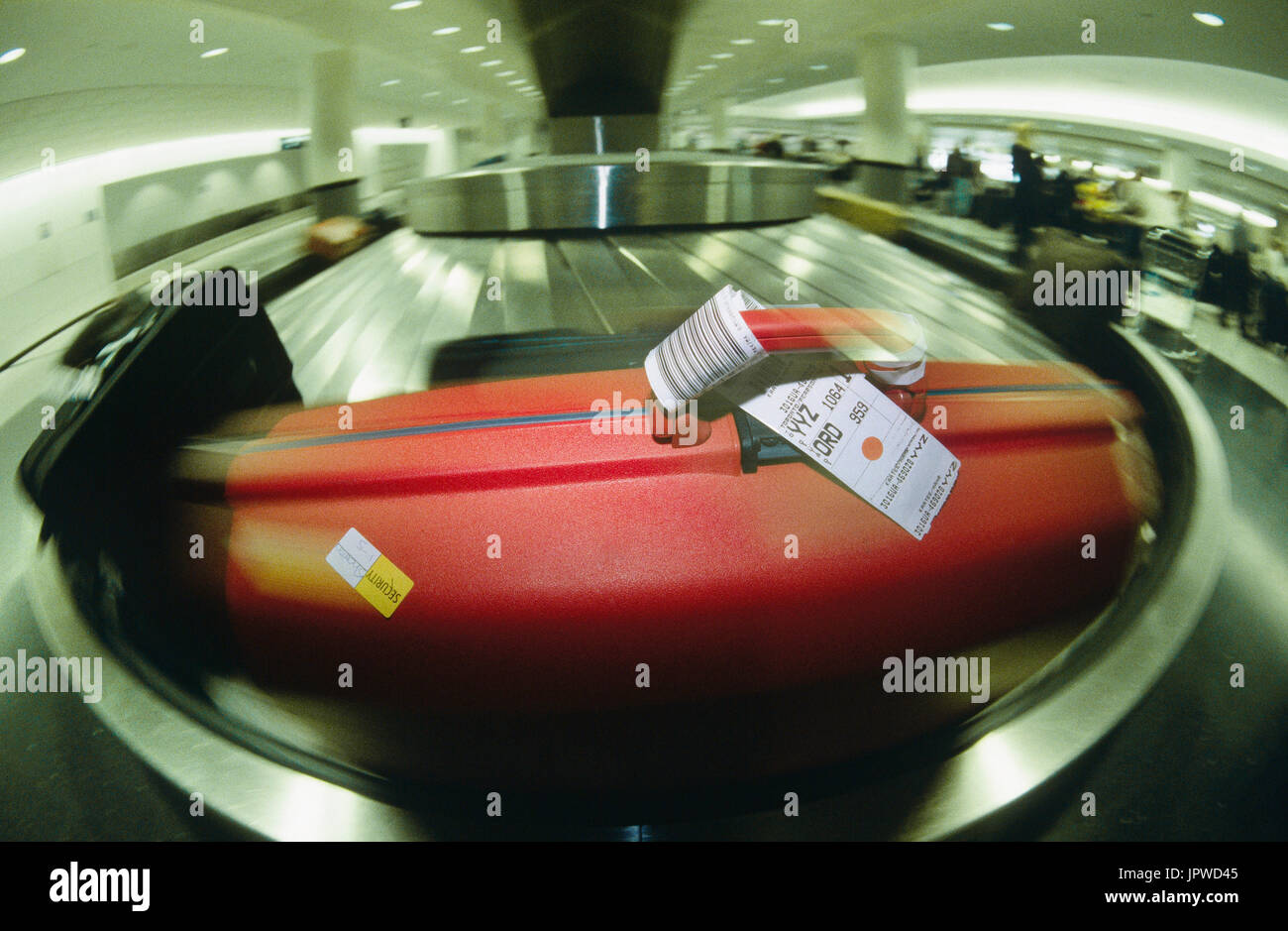 big red suitcase with baggage-tags and labels on baggage-reclaim ...