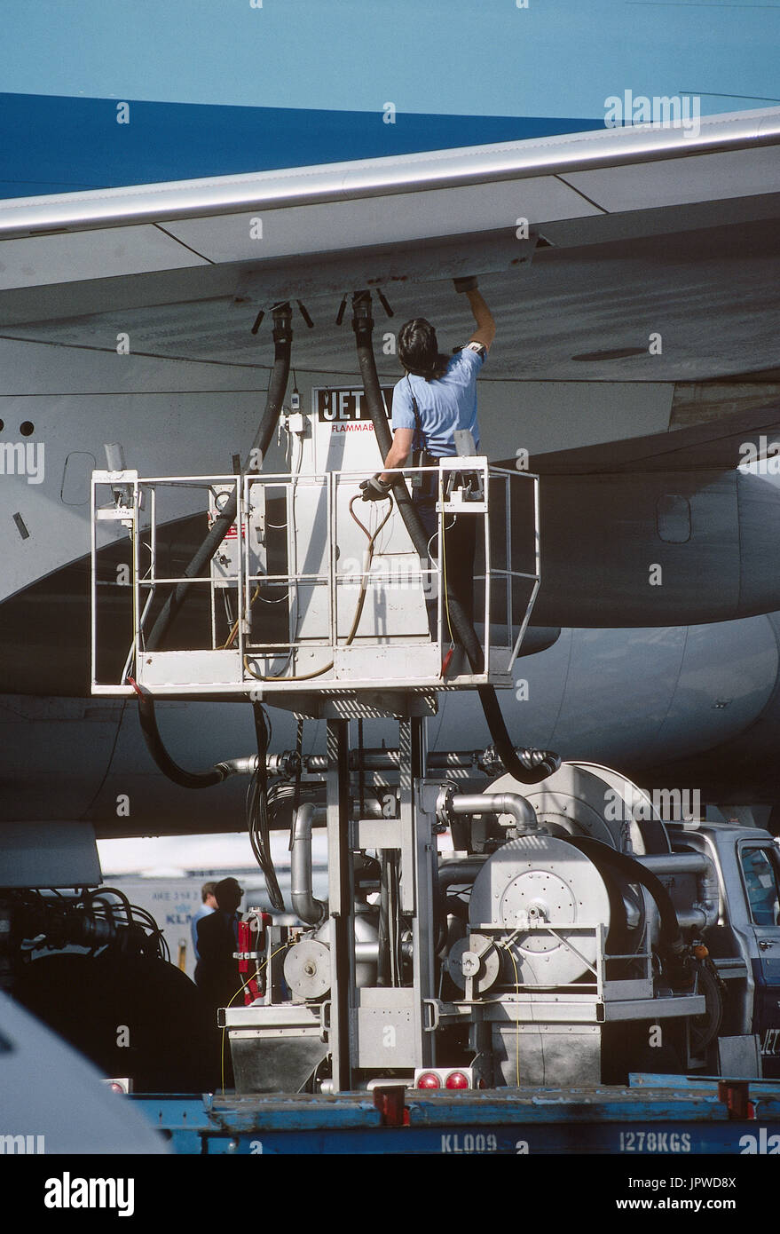 refueller monitoring two fuel-hoses attached to the underside of the ...
