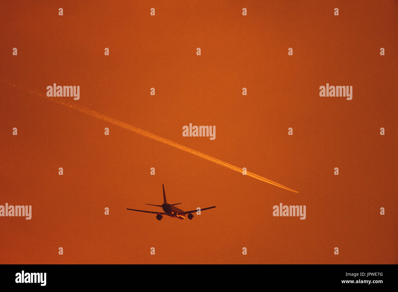 Boeing 757-200 flying enroute with an airliner contrail above at dusk ...