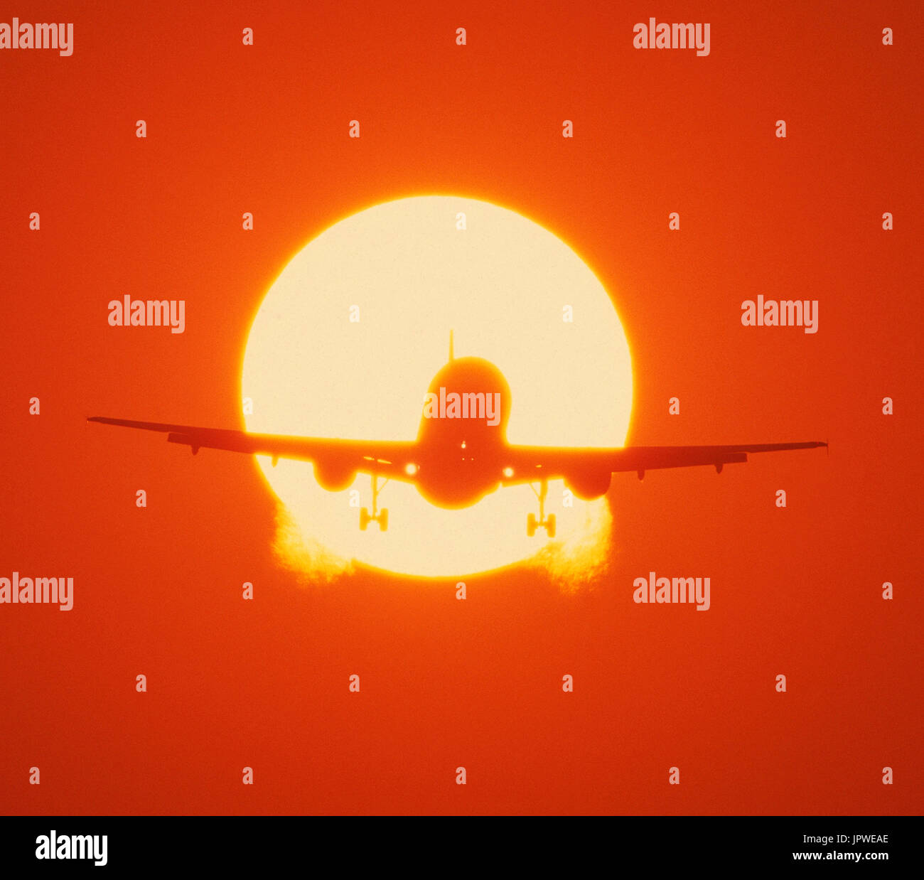 Airbus A320 on final-approach at sunset flying through the setting sun ...