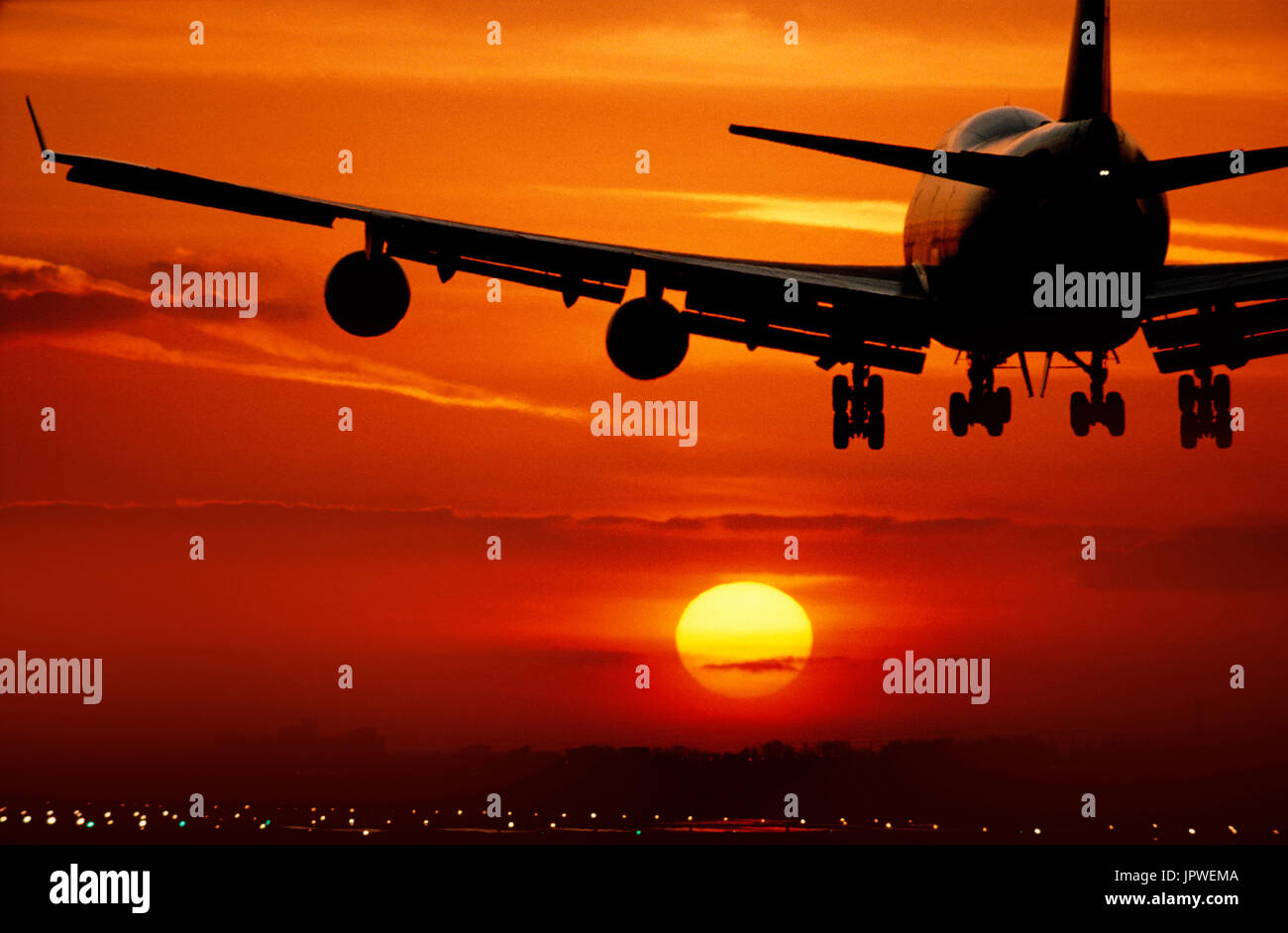 Boeing 747-400 landing on the runway at sunset with runway-lights on ...