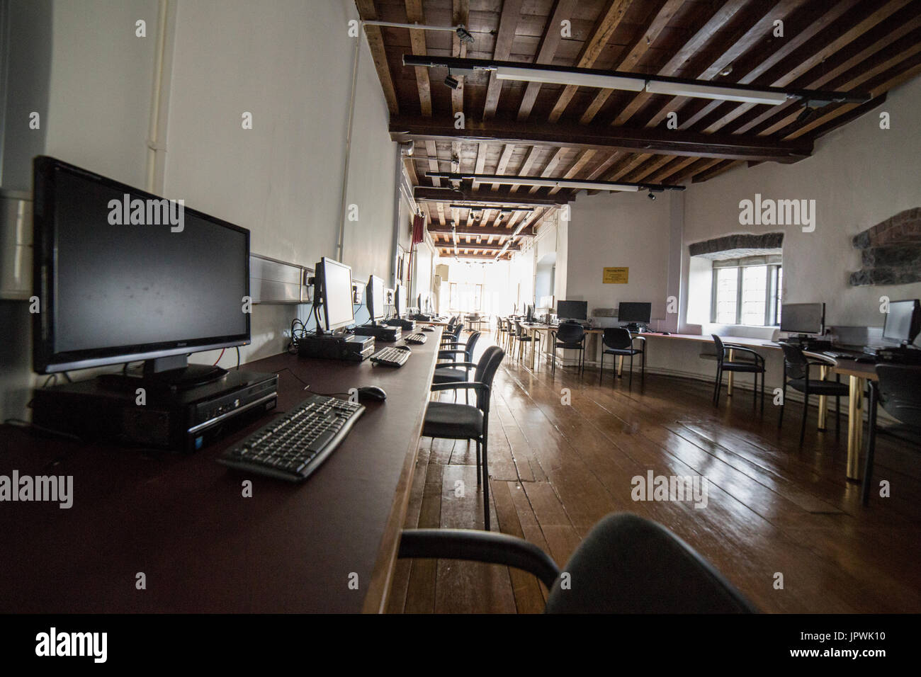 A row of computer desks in an old, wooden floored room Stock Photo - Alamy