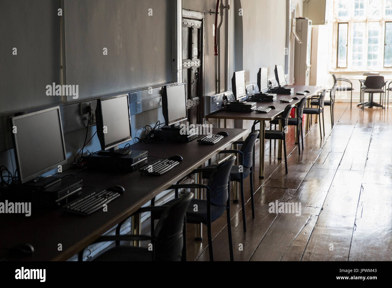 A row of computer desks in an old, wooden floored room Stock Photo - Alamy