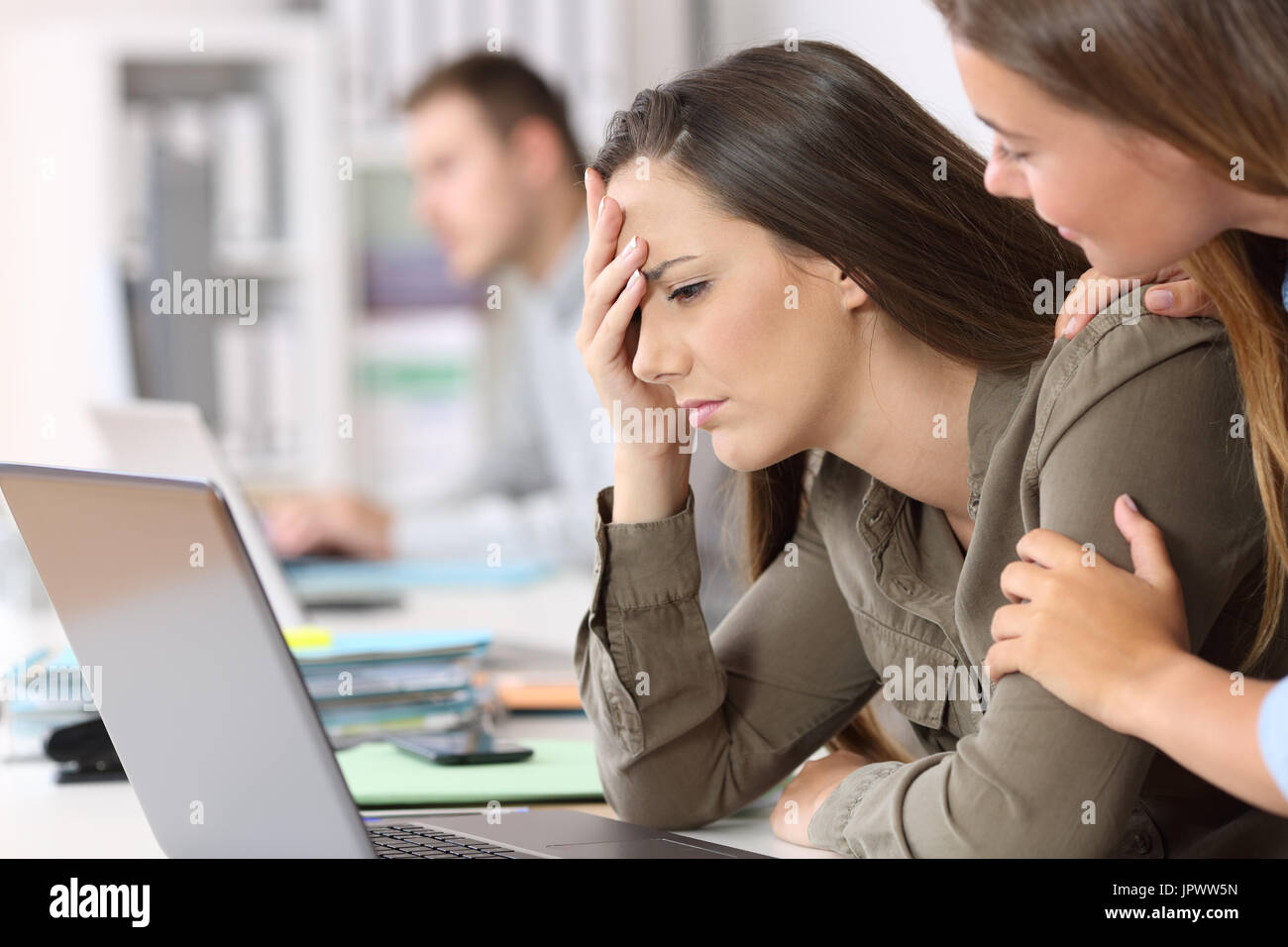 Sad employee receiving bad news on line being comforted by a colleague ...