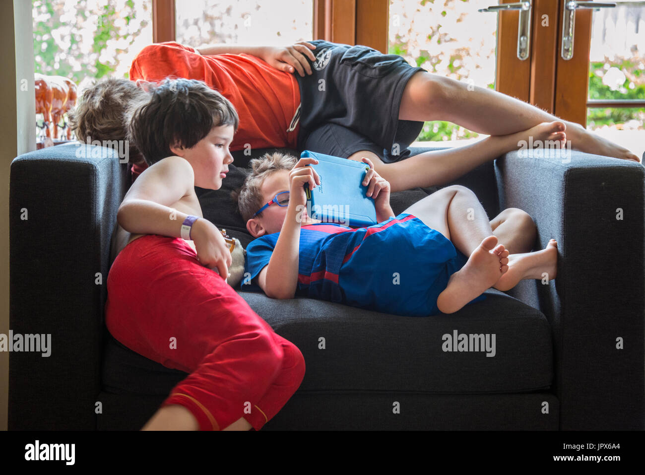Young Boy Playing Games on iPad with 2 other boys looking on Stock ...