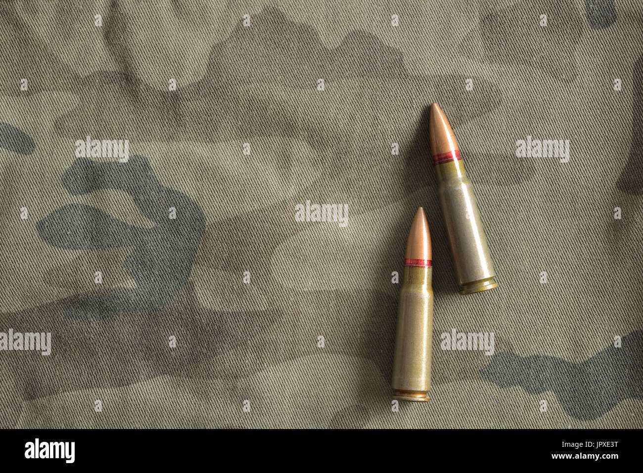 Two rifle bullets on military camo. Military ammunition Stock Photo - Alamy