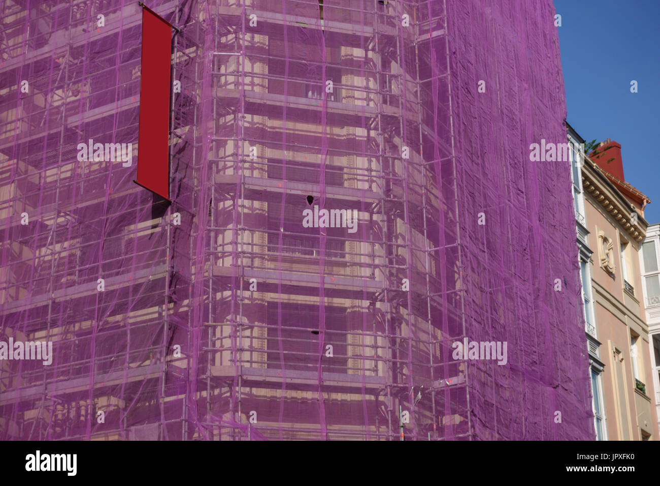 Scaffolding covered with net and blank poster Stock Photo - Alamy