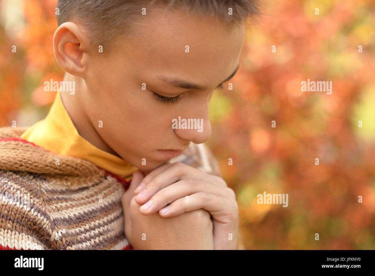 Portrait of sad boy in autumn park praying Stock Photo - Alamy