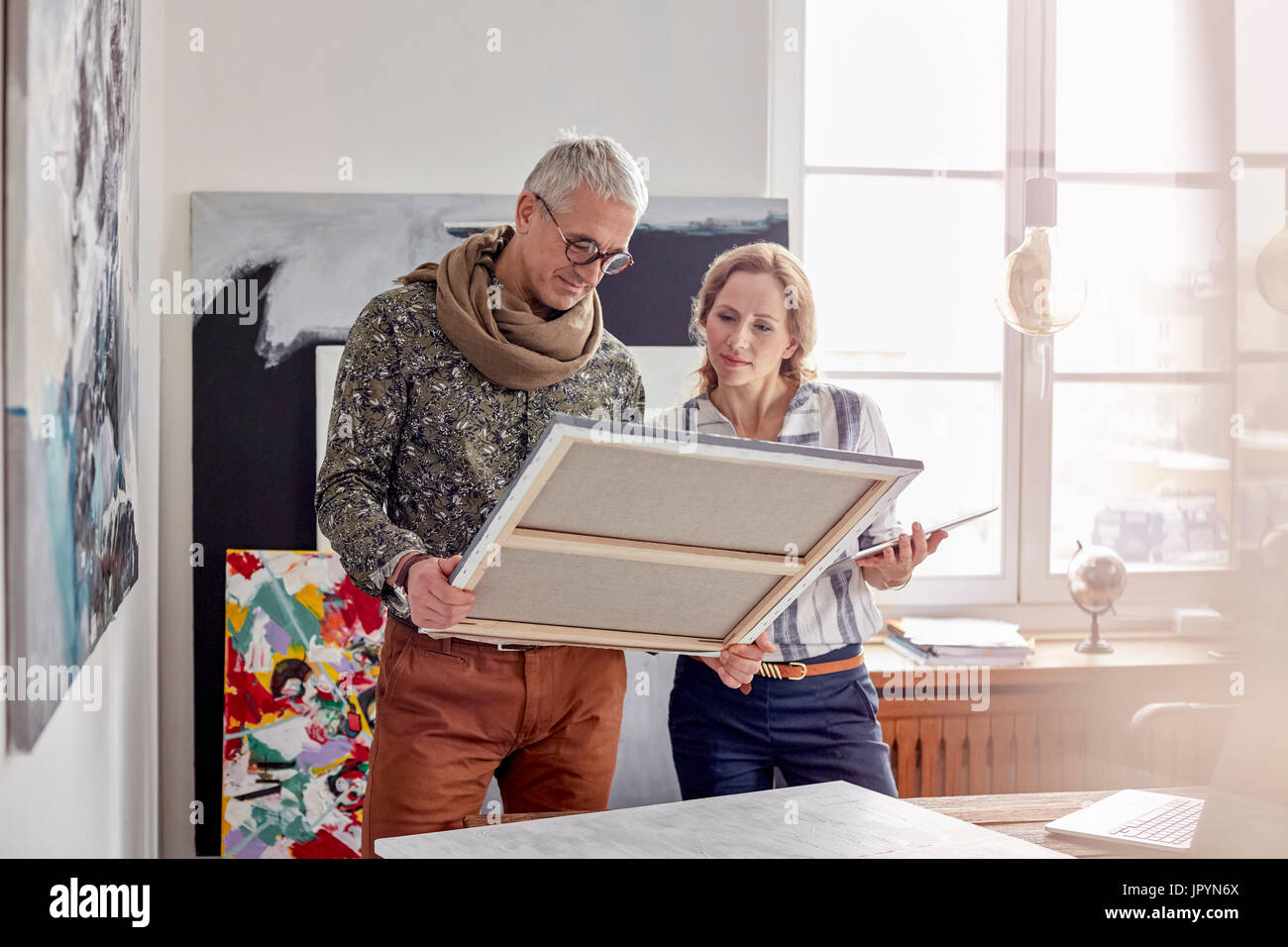 Painters examining painting in art studio Stock Photo - Alamy
