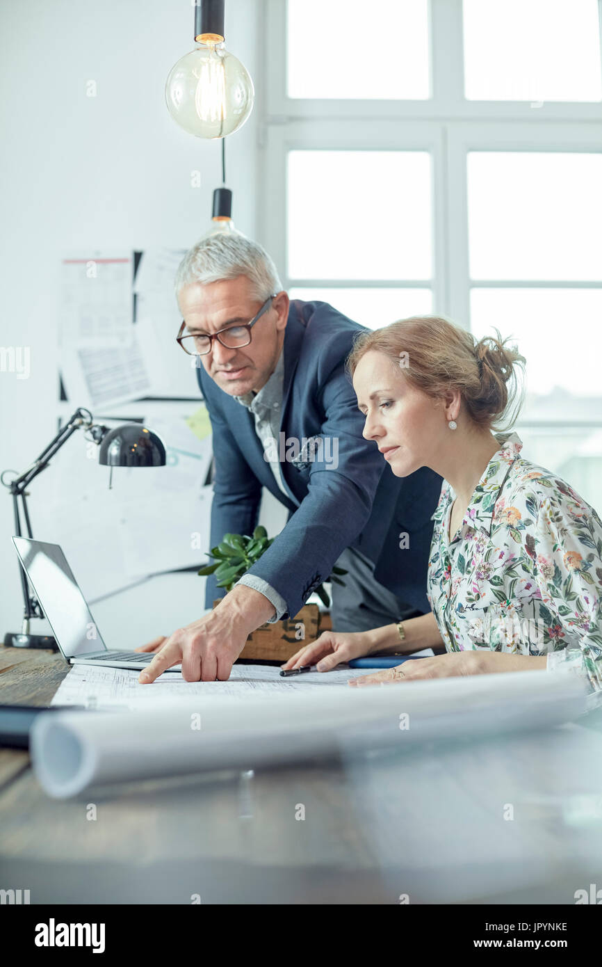 Architects discussing, reviewing blueprints in office Stock Photo - Alamy