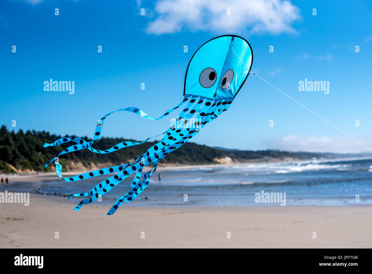 Blue kite with eyes and polka dots being flown at the beach with a blue ...