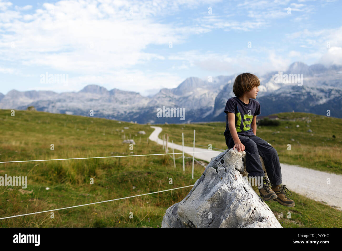 Young boy sitting on a rock on the Highlands of Montasio (Altopiano del ...