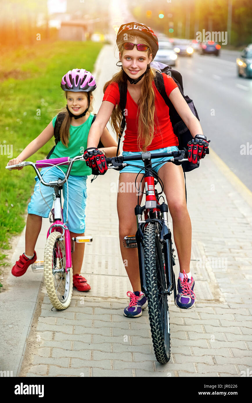 Girls children cycling on yellow bike lane. There are cars on road ...