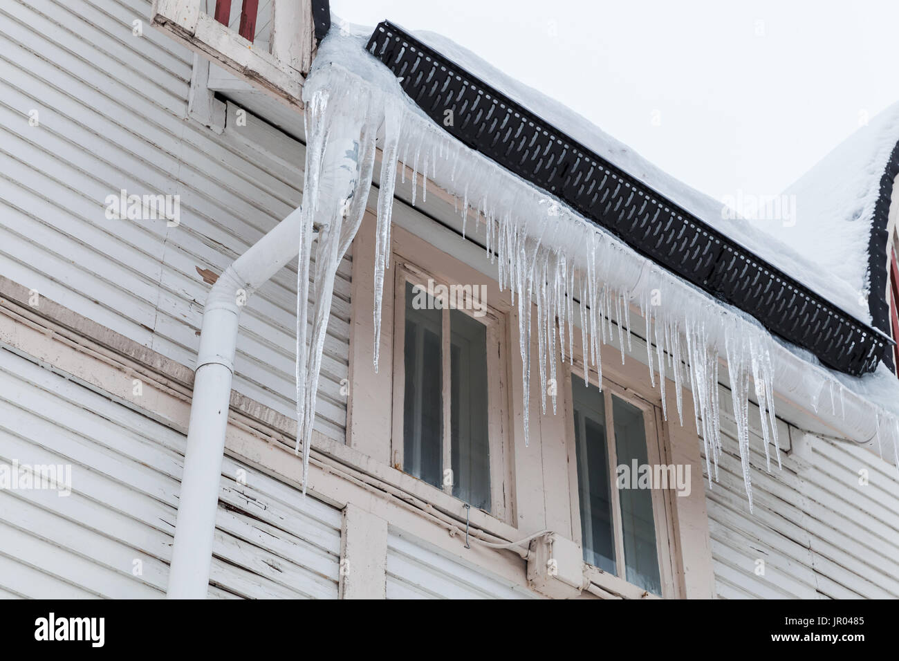 Large icicles hang on the facade of wooden living house. European ...