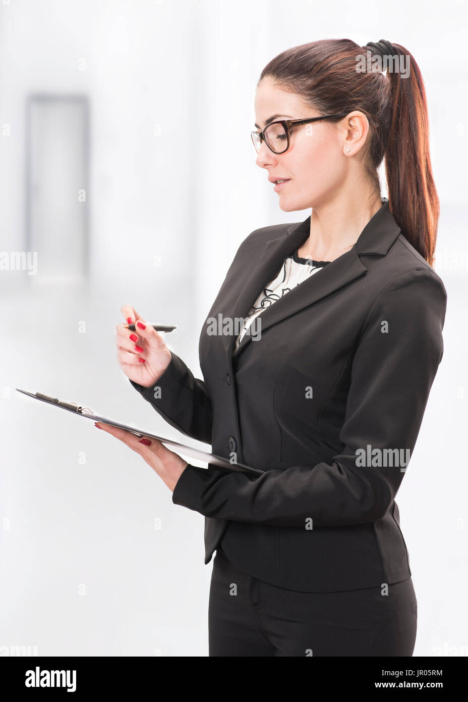 Brunette business woman with a checklist thinking Stock Photo - Alamy