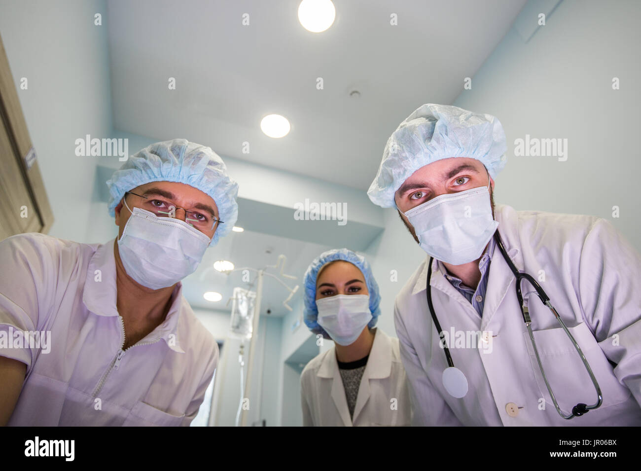 Below view of surgeons holding medical instruments in hands and looking ...