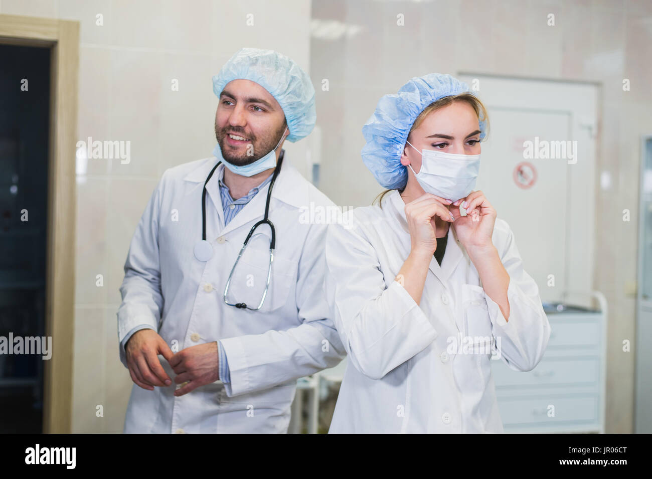 Confident female doctor putting on medical face mask while preparing ...