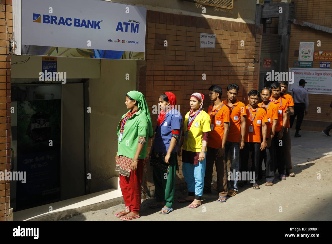 Ready-made garment workers use ATM booth services outside of a factory ...